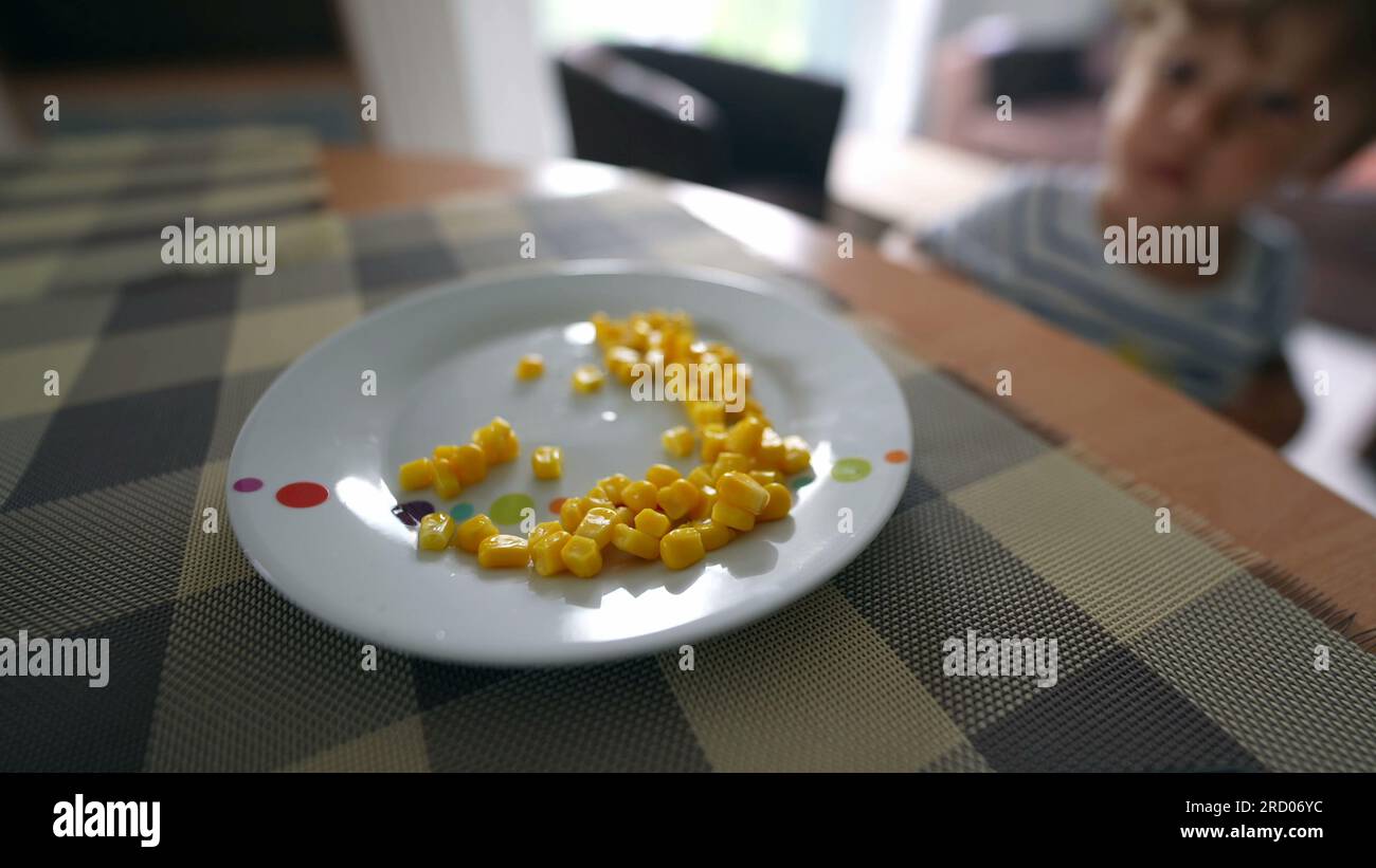 Child grabs corn from plate little boy grabbing food Stock Photo - Alamy