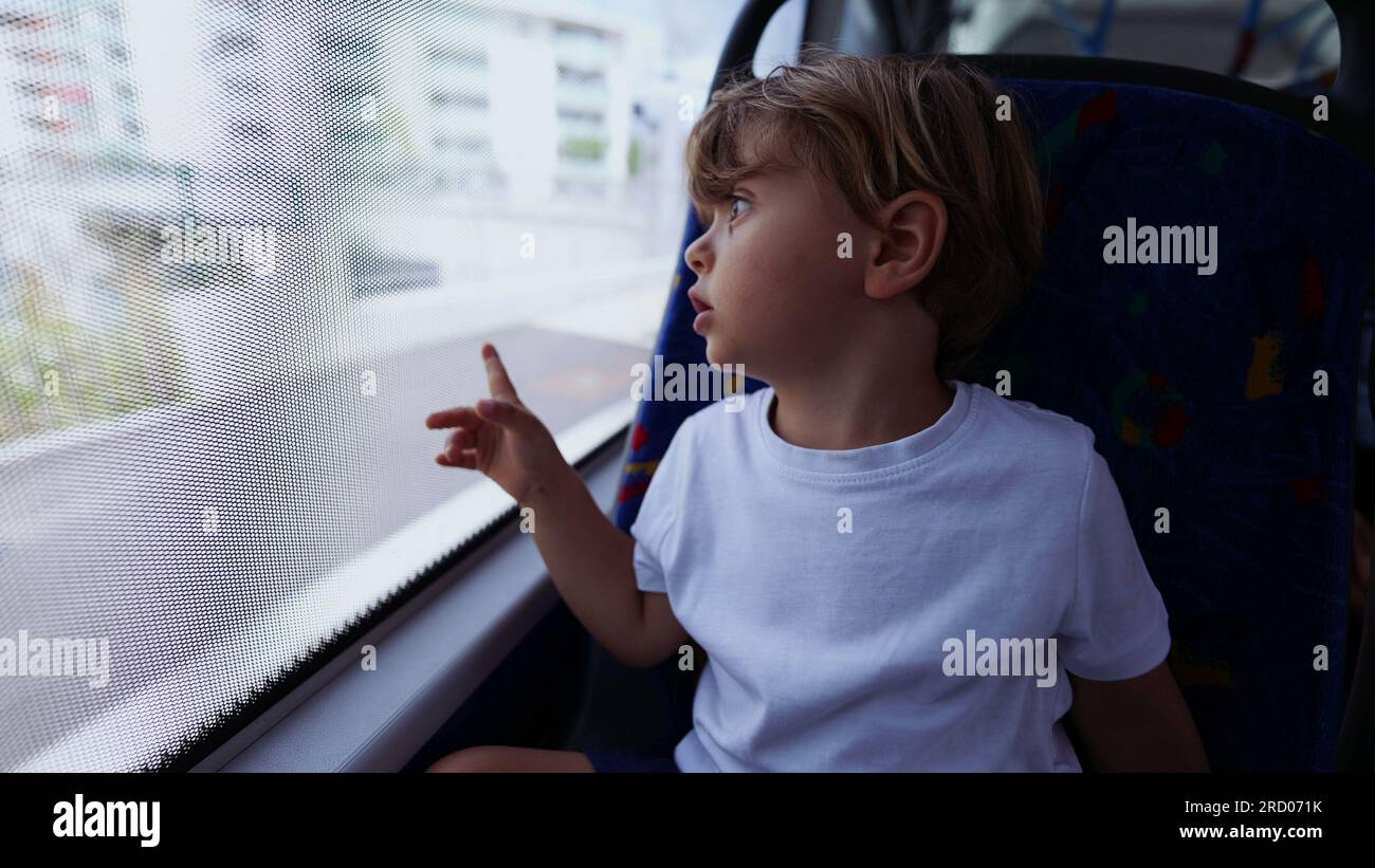 Child looking through bus window pointing city passenger kid on public ...