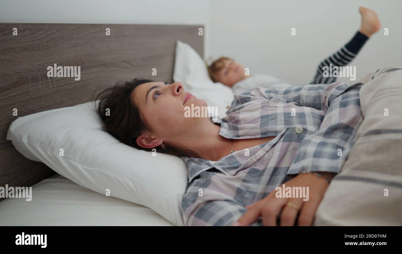 Mother in bed with child waking up in the morning yawning starting the ...