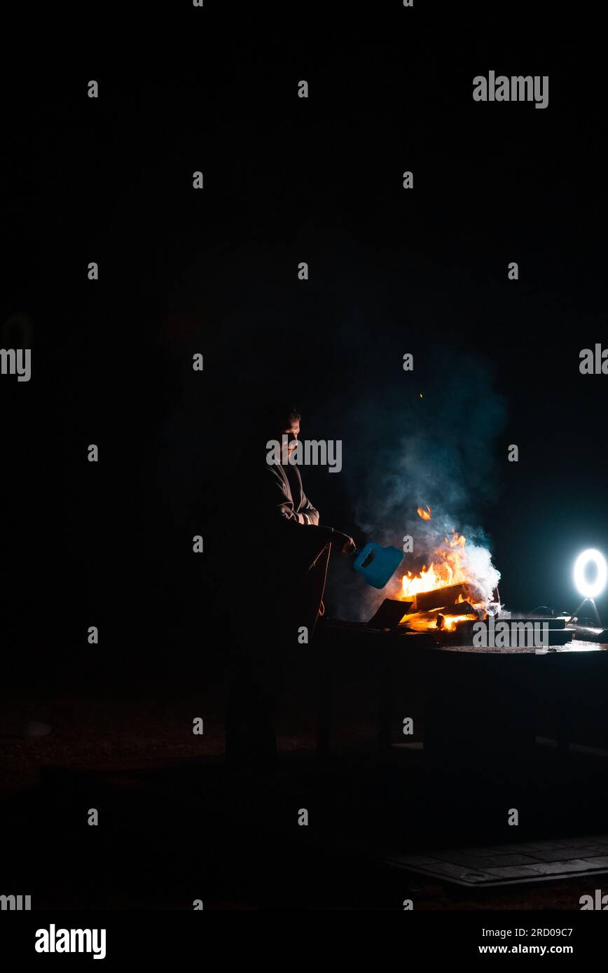 Man preparing bbq grill to cook on fire. Outside dark shot. Freeze ...