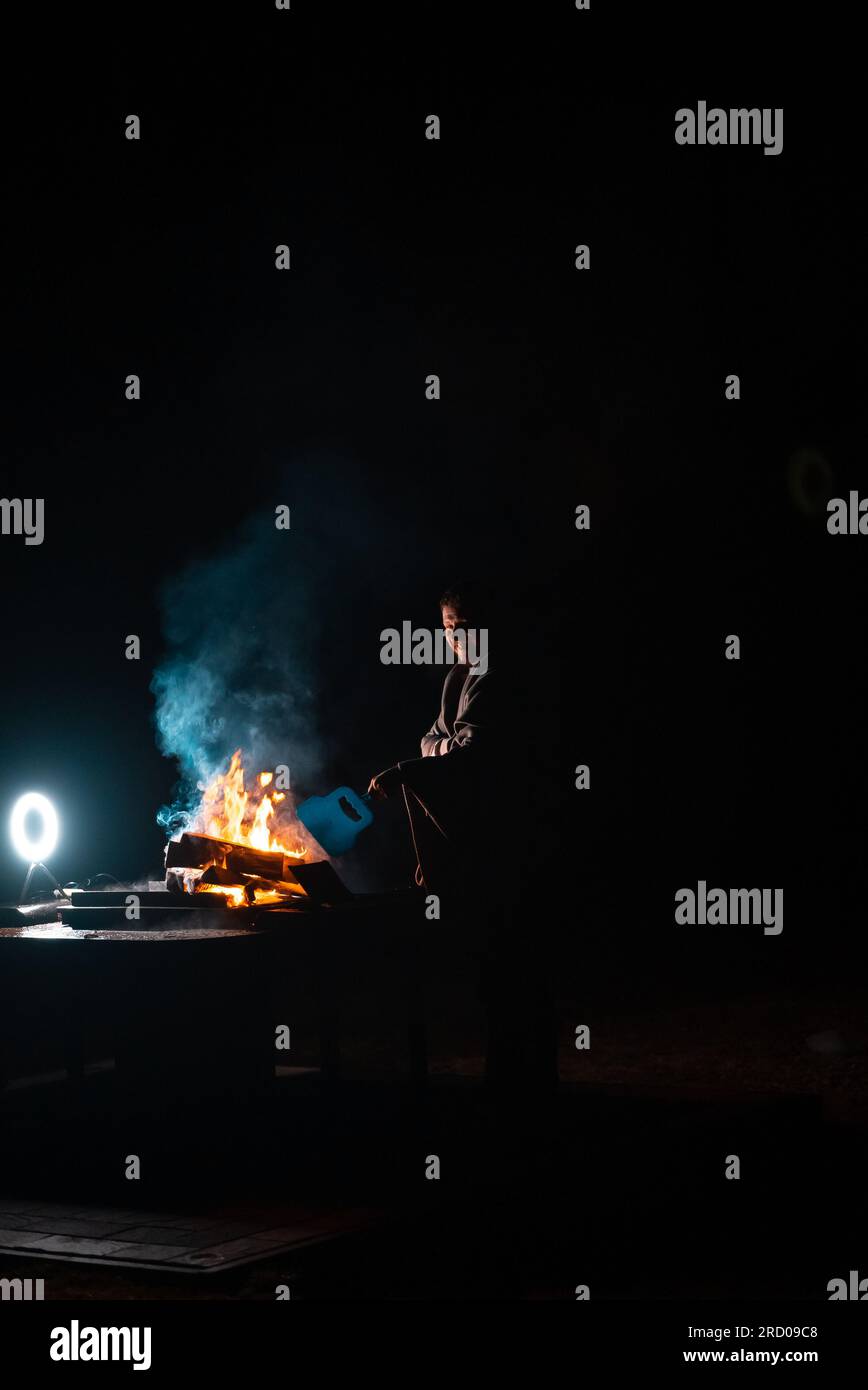 Man preparing bbq grill to cook on fire. Outside dark shot. Freeze ...