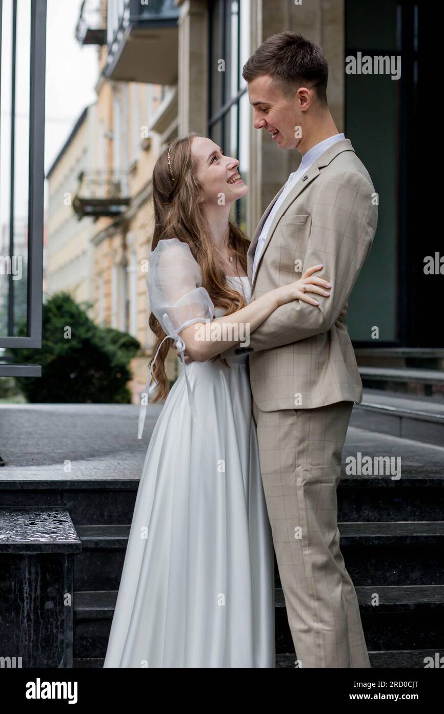 The bride looks at the groom with loving eyes. Smiling newlyweds look ...
