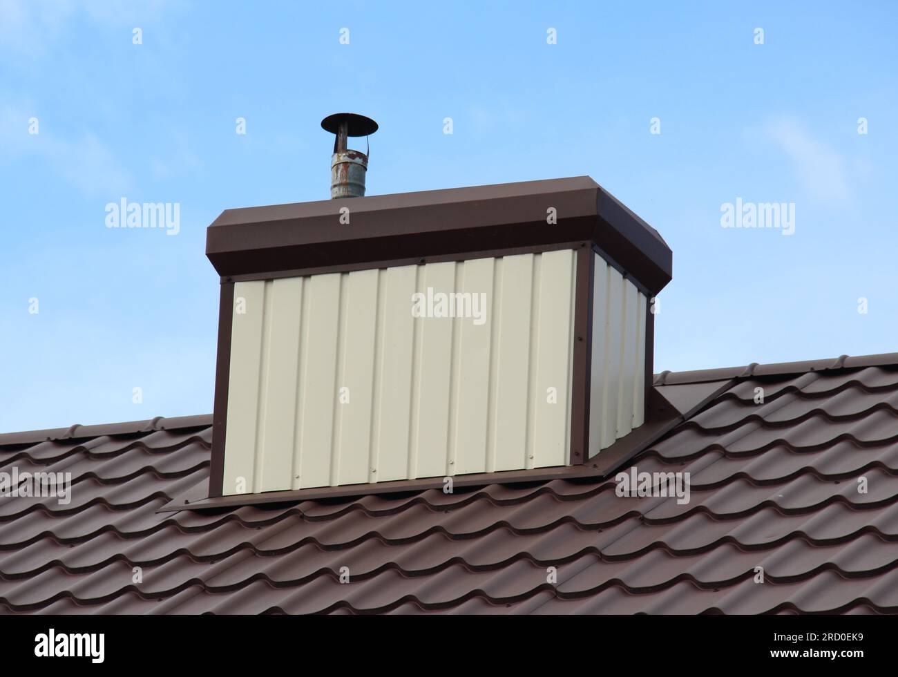 A chimney on the roof of a house covered with metal tiles or a metal ...