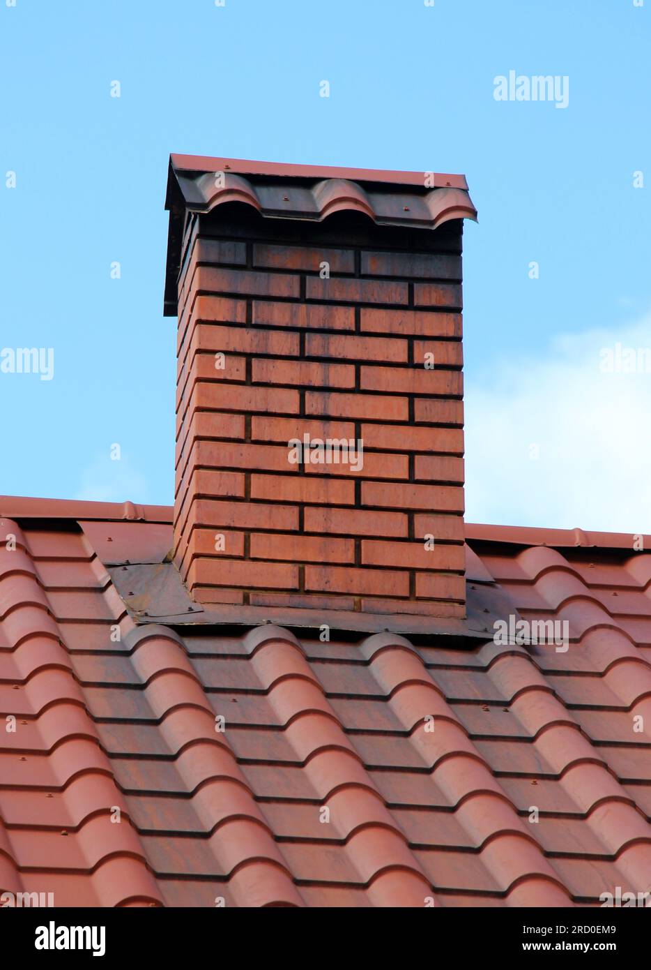 A chimney on the roof of a house covered with metal tiles or a metal ...