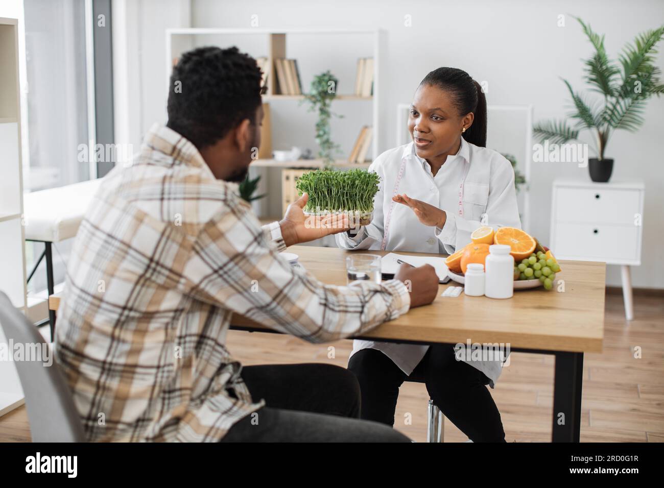 Attractive woman in lab coat giving consultation to adult man about ...