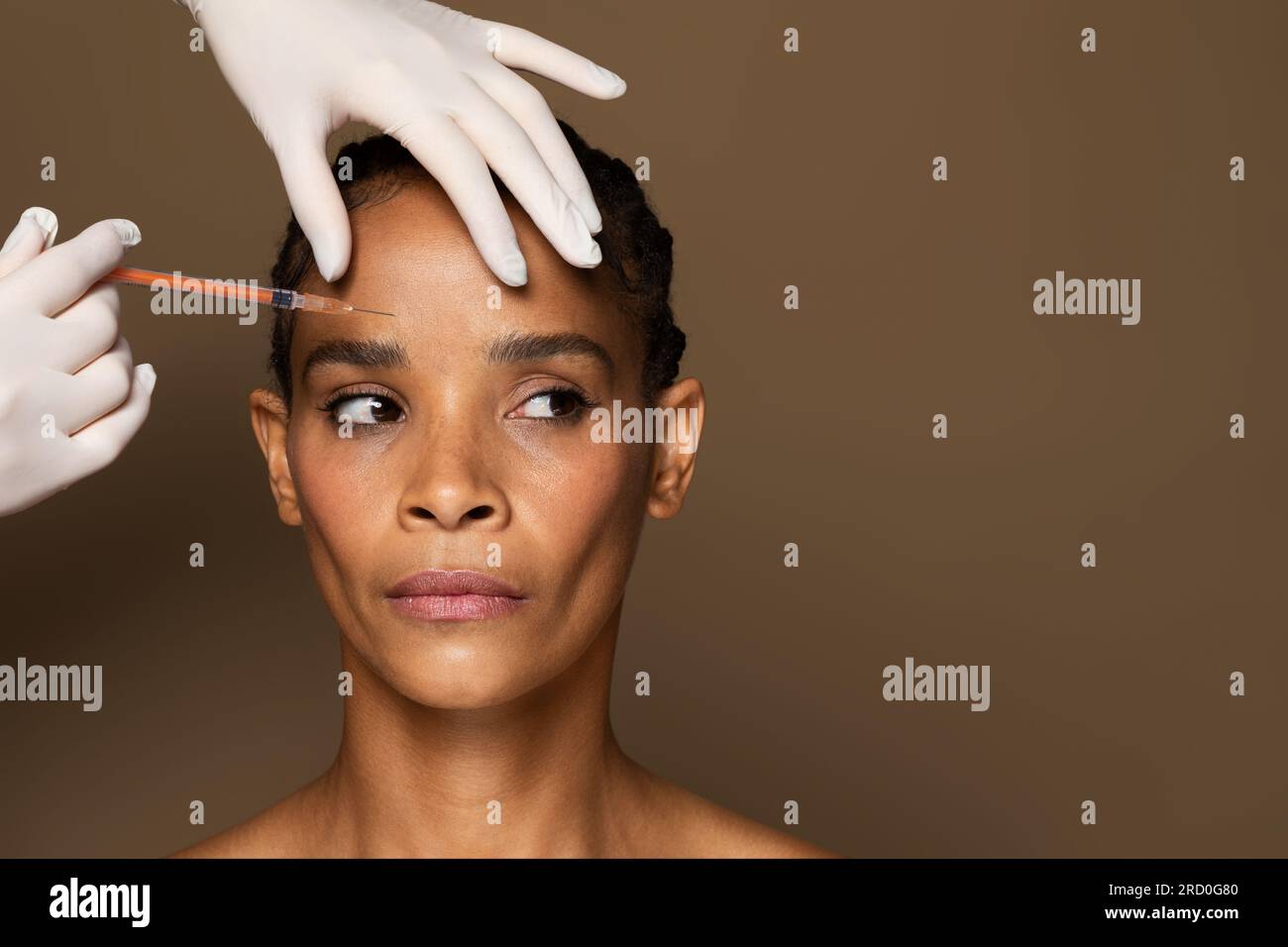 Cosmetologist boctor making botox injection in interbrow zone to black ...