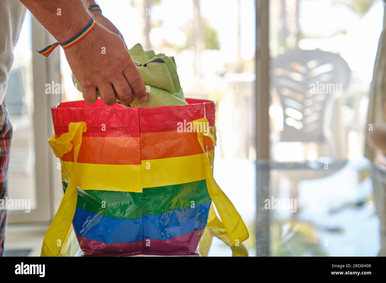 Unrecognizable man with color hand band standing and putting clothes in ...