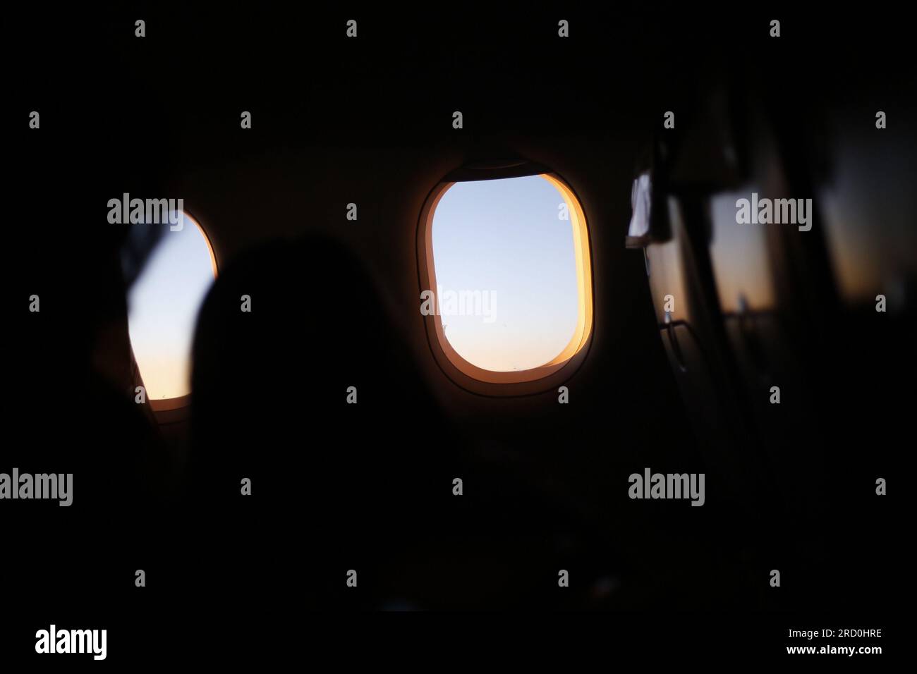 Commercial airplane window view of a blue sunrise sky and black ...