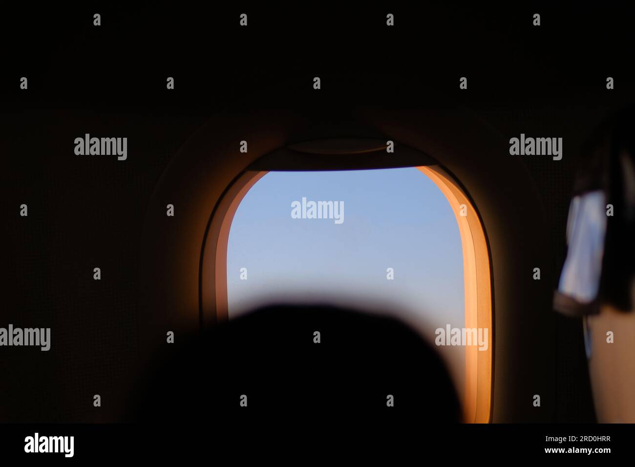 Commercial airplane window view of a blue sunrise sky and black ...