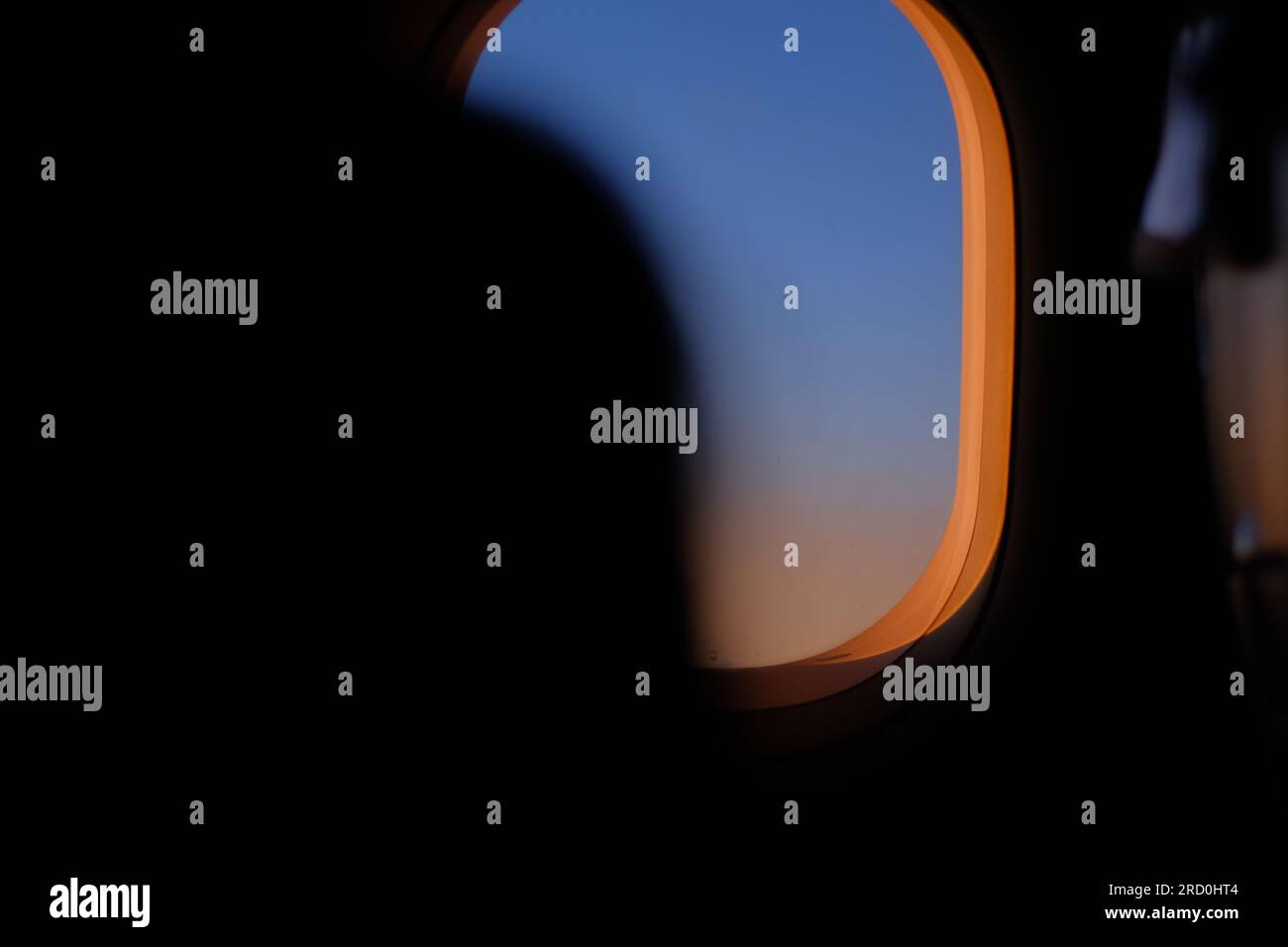 Commercial airplane window view of a blue sunrise sky and black ...