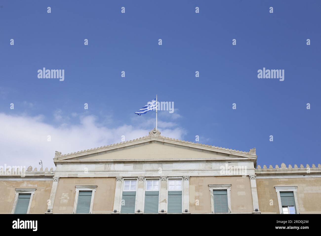 Athens Parliament facade building with Greek flag waving on a blue sky ...