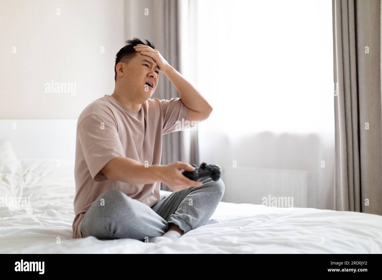 Upset asian man loser playing video games at home Stock Photo - Alamy