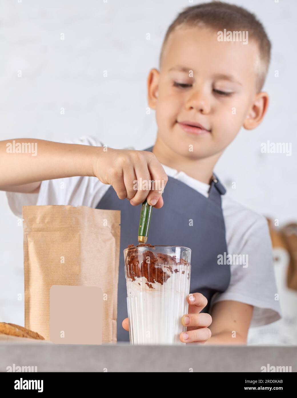 Cute boy cooks hot chocolate from cocoa powder and milk. Hot cacao ...