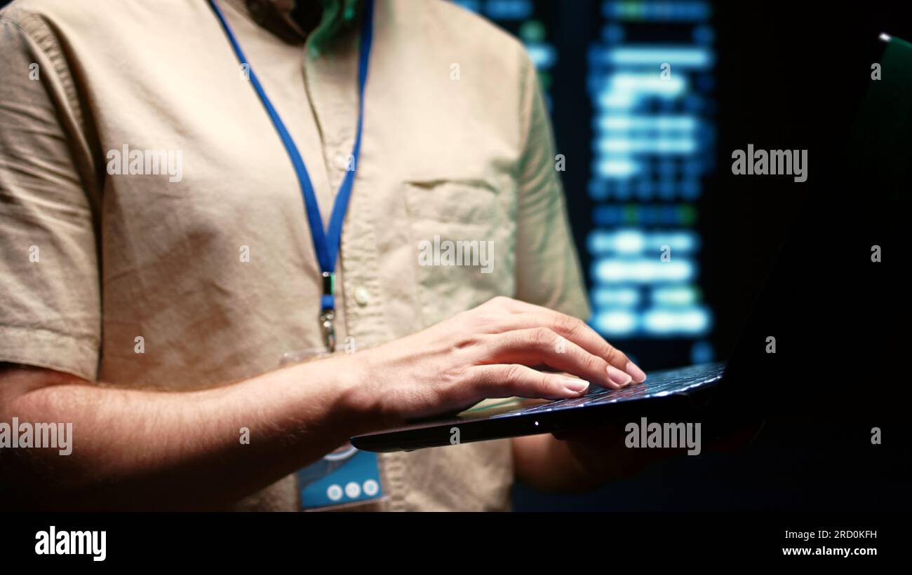 Close up of system administrator using laptop to check operational server clusters. Rackmounts ...