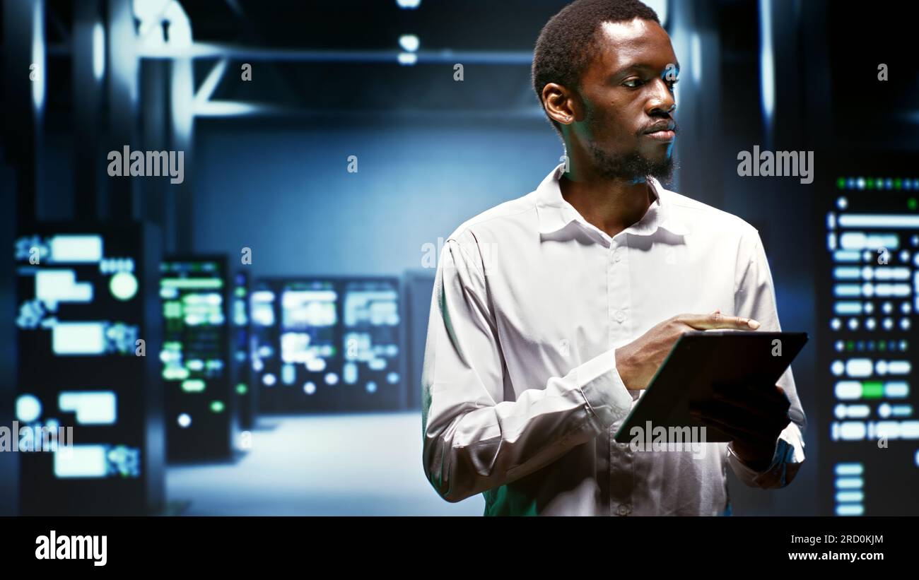 Cheerful electrician inspecting server hub providing vast computing resources and storage ...