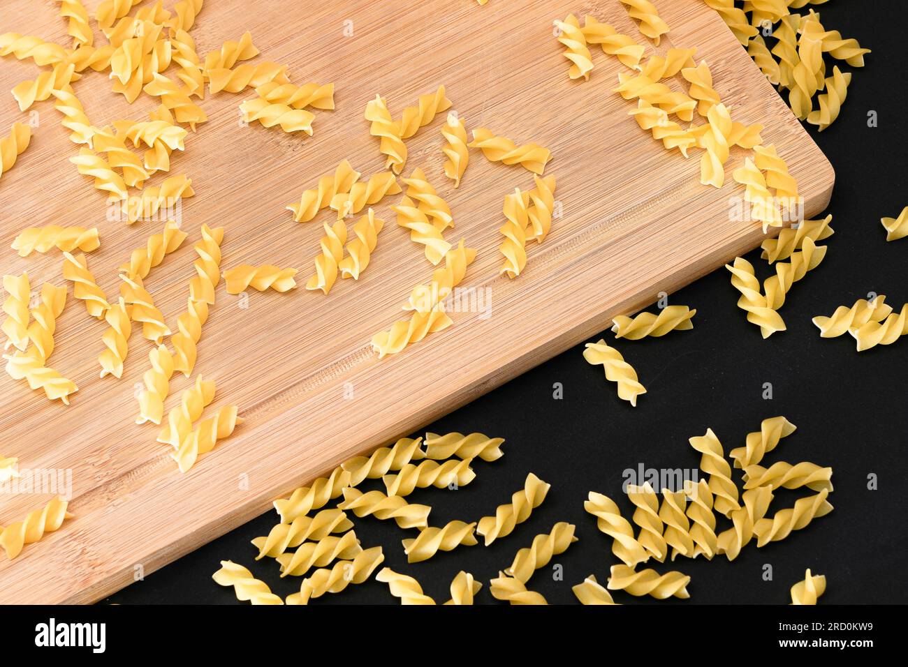Uncooked Fusilli Pasta Scattered on Wooden Board and Black Table. Raw ...