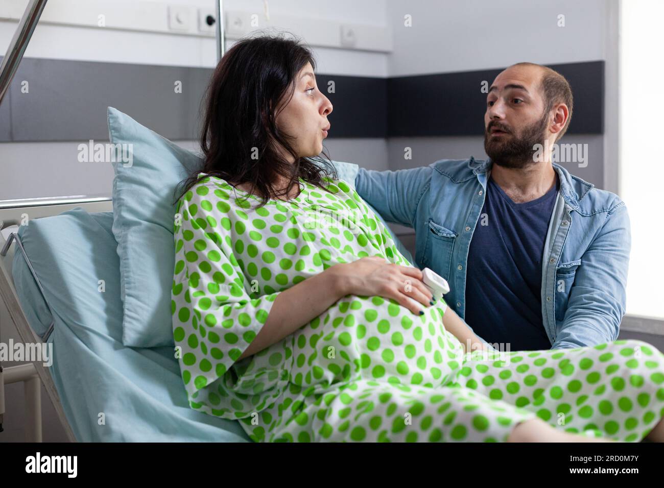 Pregnant woman going into labor in hospital ward, husband standing ...