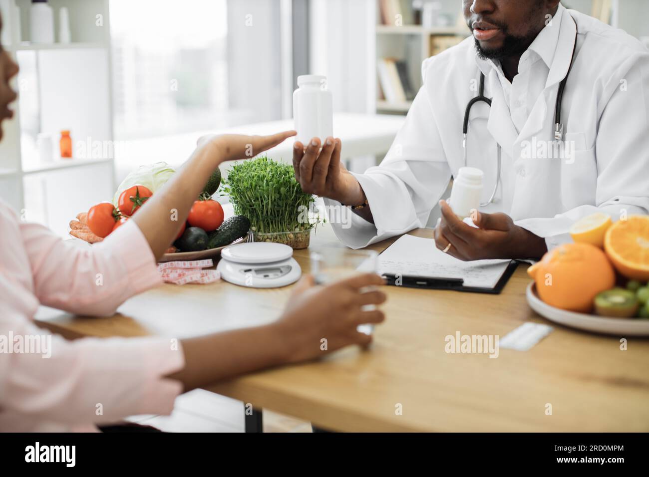 Crop of male dietitian providing expert check-up and giving nutritional supplements to female ...