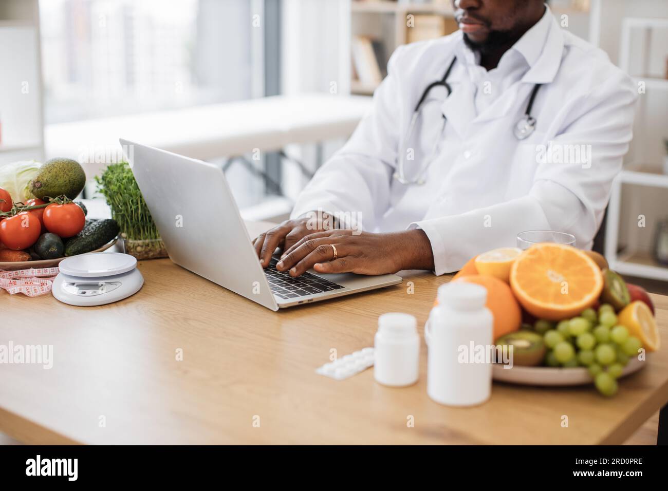 Crop of african american dietitian sitting at table with healthy food ...