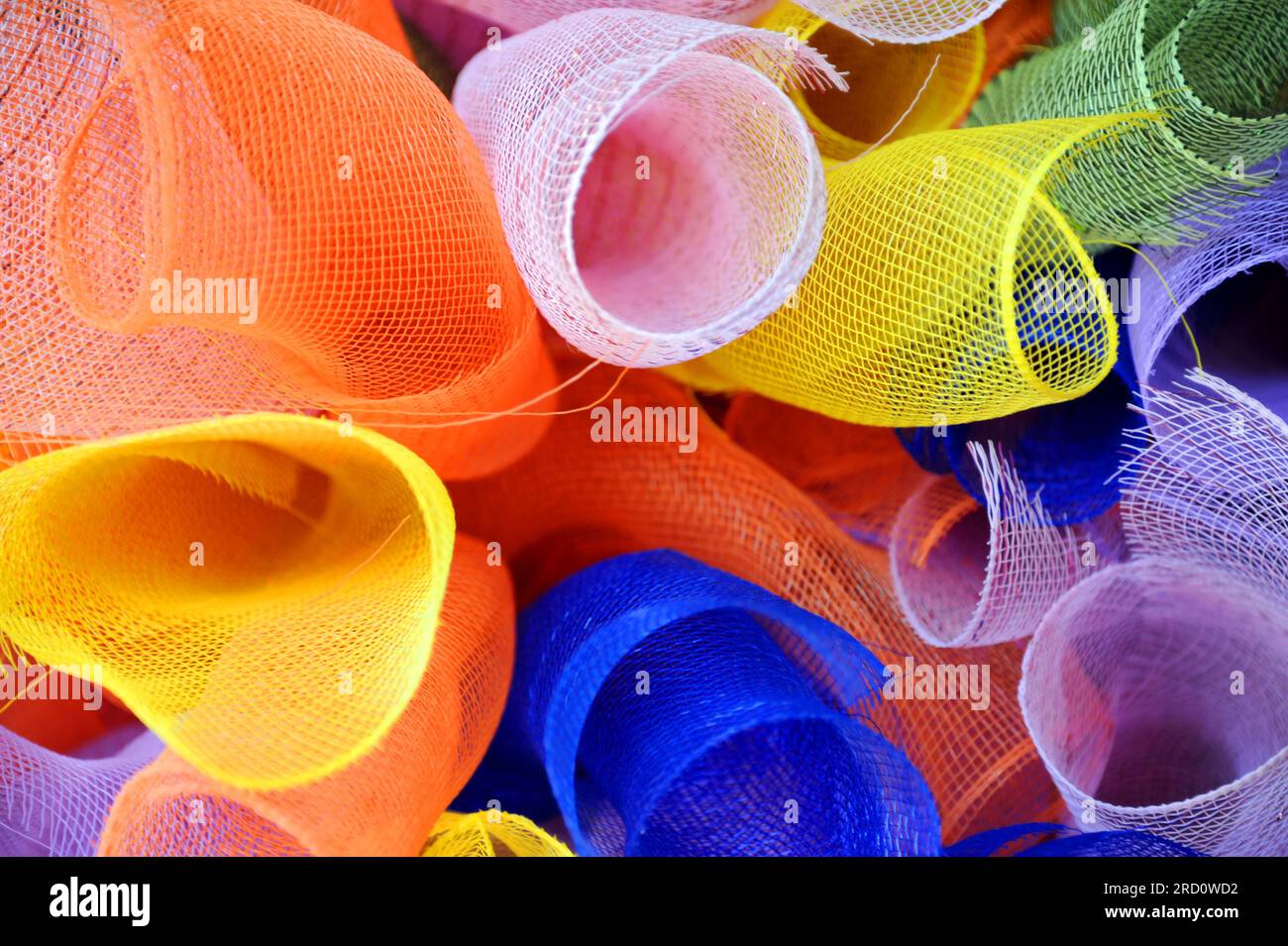 Colorful rolls of craft netting lays in a bunch. Angle shows end of ...