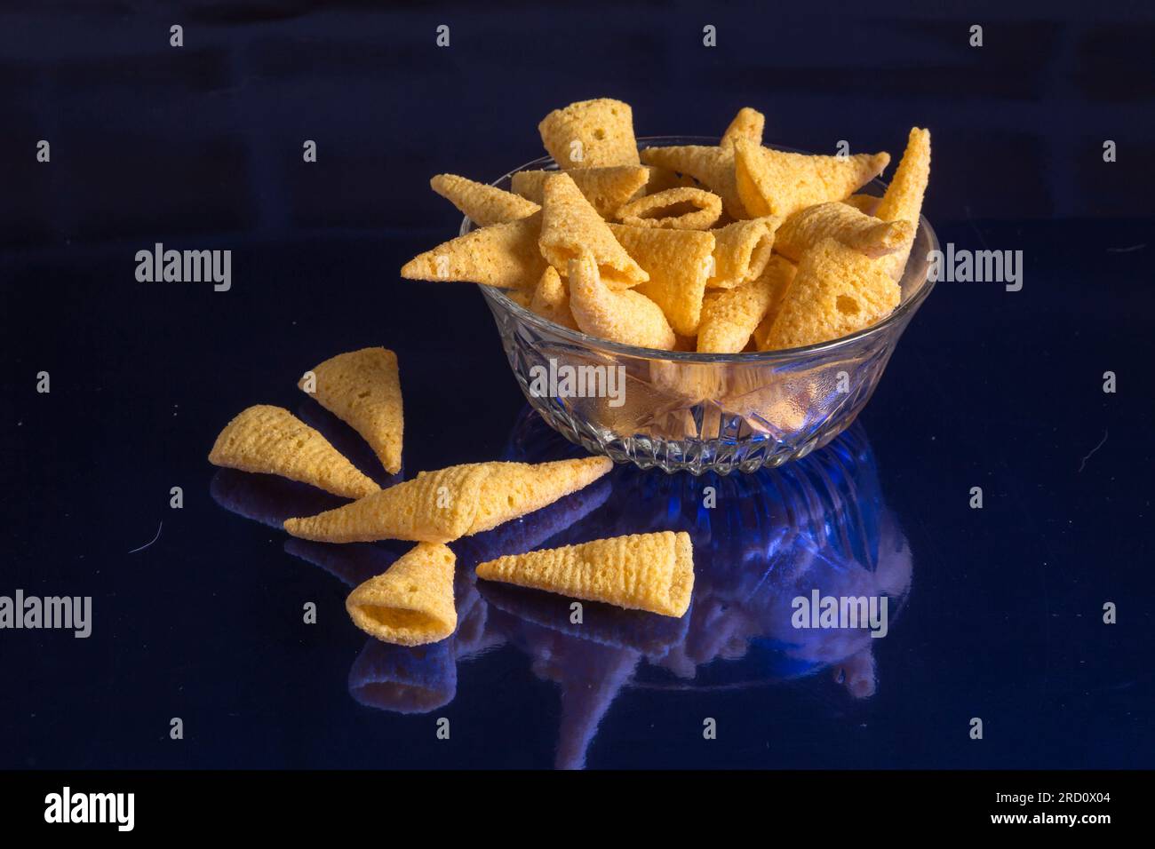 view of a bowl with snacks, corn cones, some fallen in the foreground ...