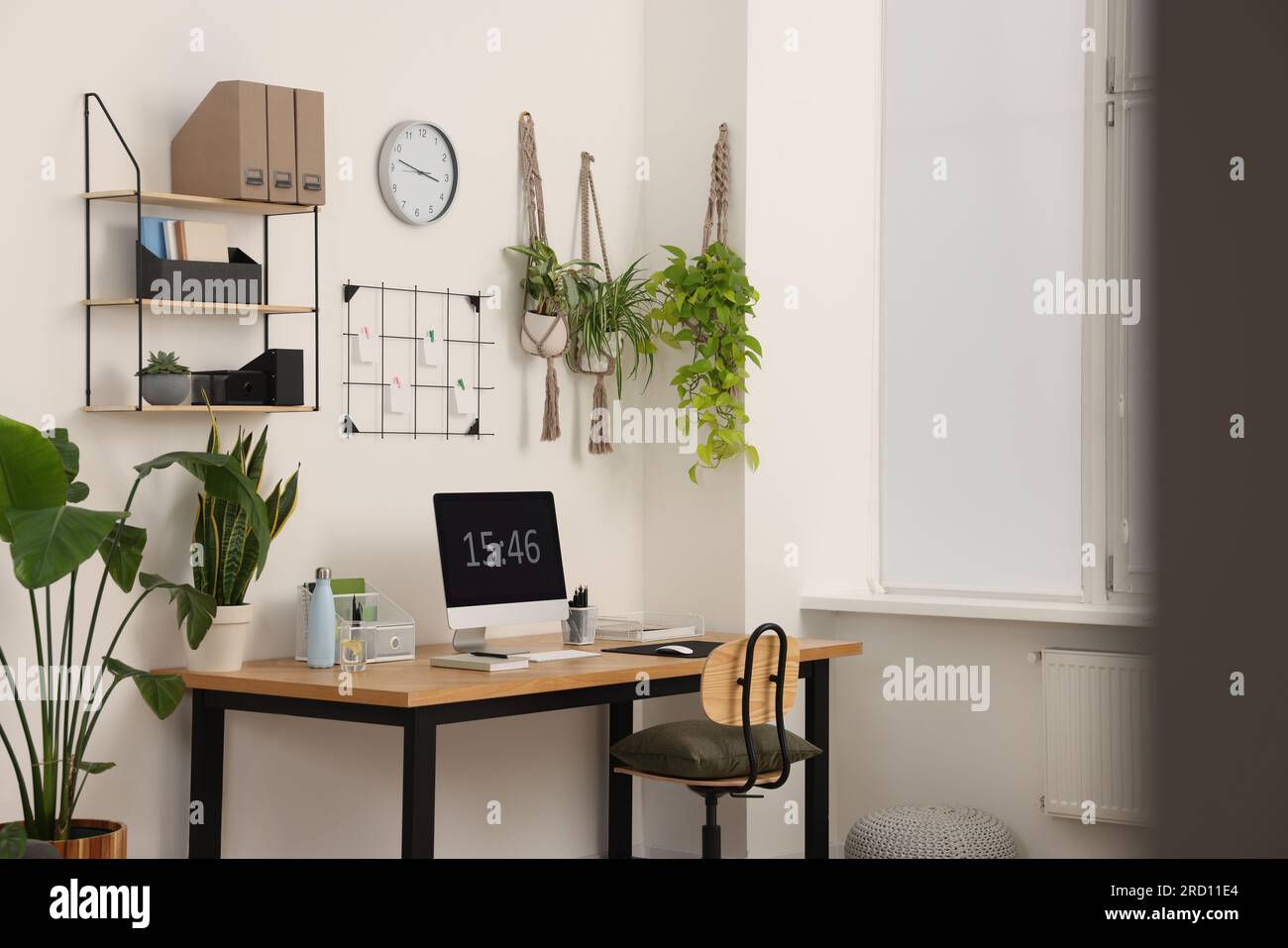 Cozy workplace with computer, modern furniture and houseplants at home ...