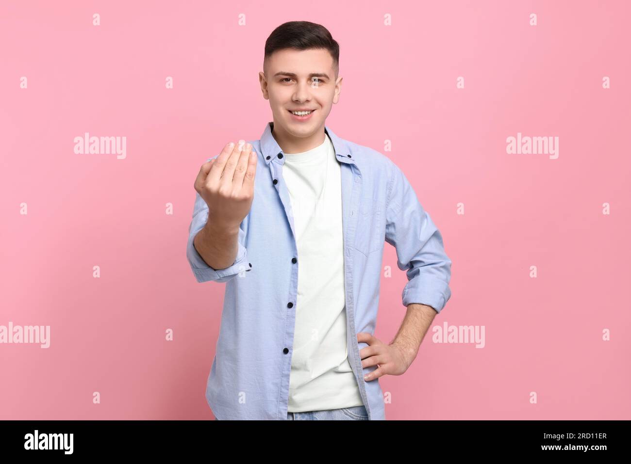 Handsome man inviting to come in against pink background Stock Photo ...