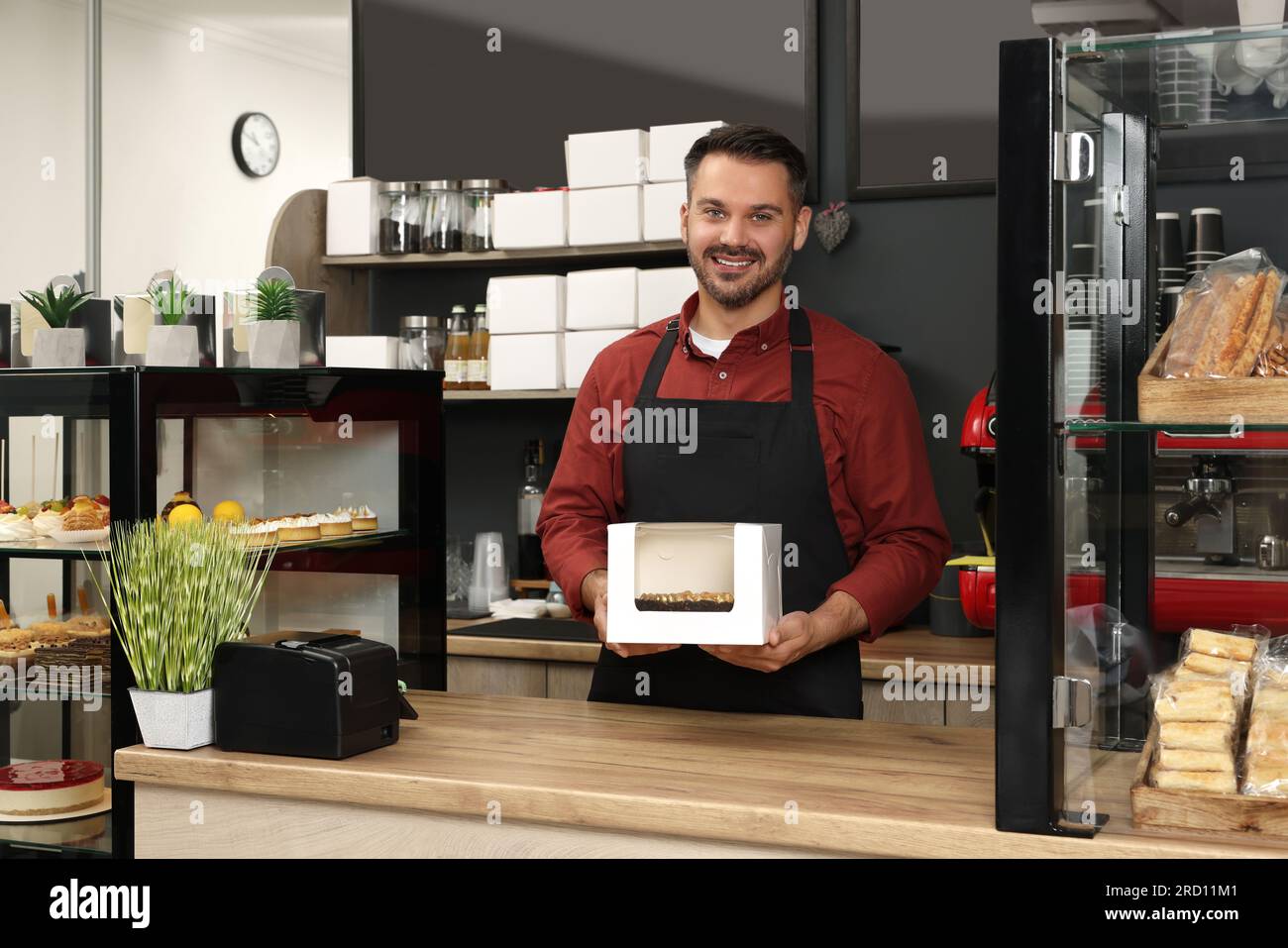 Business owner in his cafe. Man holding box with cake at desk Stock ...