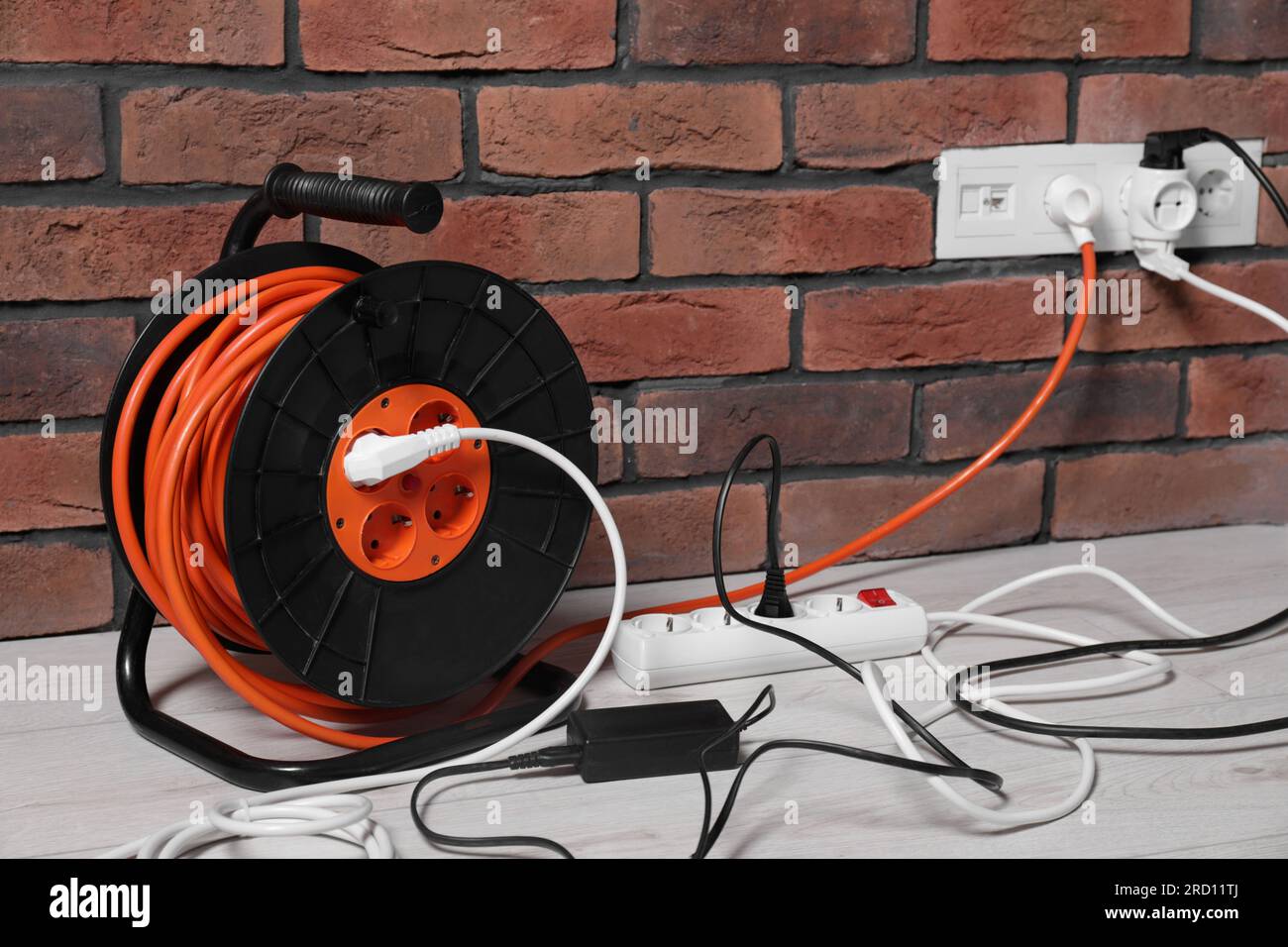 Extension cord reel plugged into socket on white laminated floor near ...