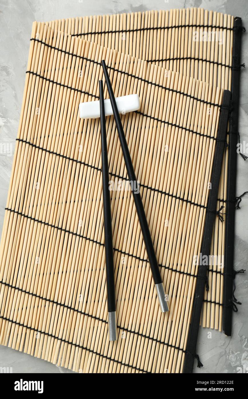 Bamboo mat with pair of black chopsticks and rest on table, top view ...