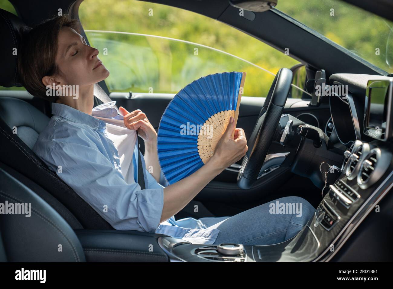 Overheated exhausted middle aged woman driver with hand fan suffering ...