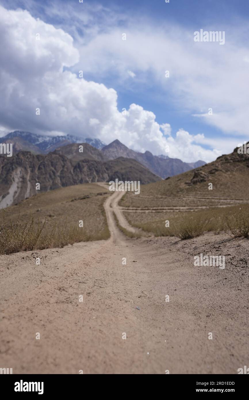 The cloudy blue sky overlooking dusty path towards the mountains Stock ...