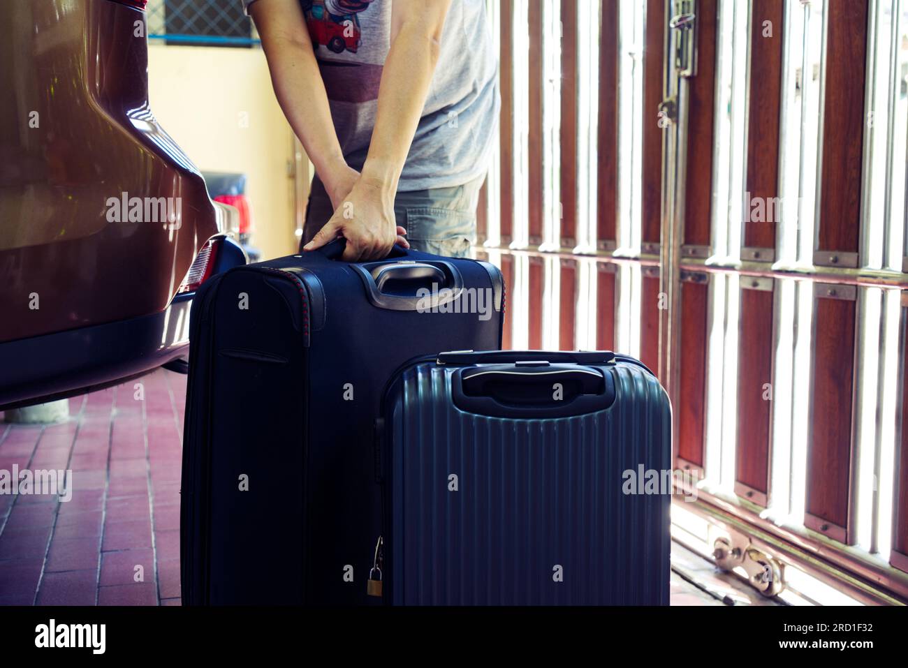 Man hand carrying a big suitcase into the trunk of an SUV in the car ...