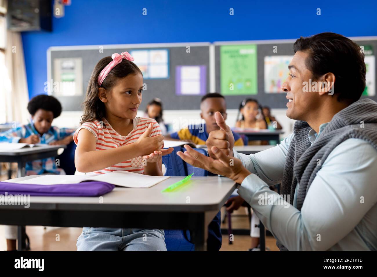 Happy diverse male teacher teaching girl using sign language in ...
