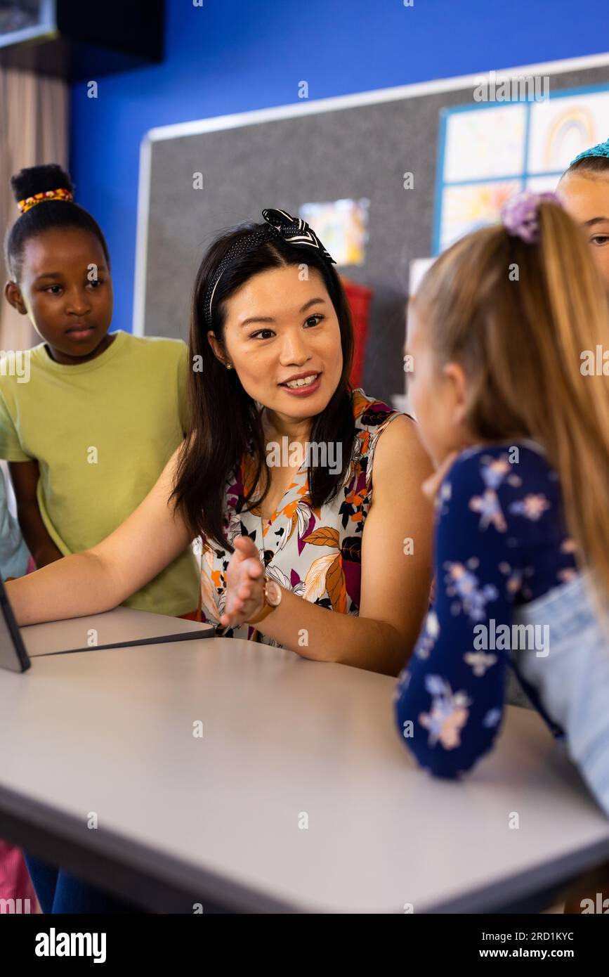 Diverse female teacher with tablet and elementary schoolgirls in class ...