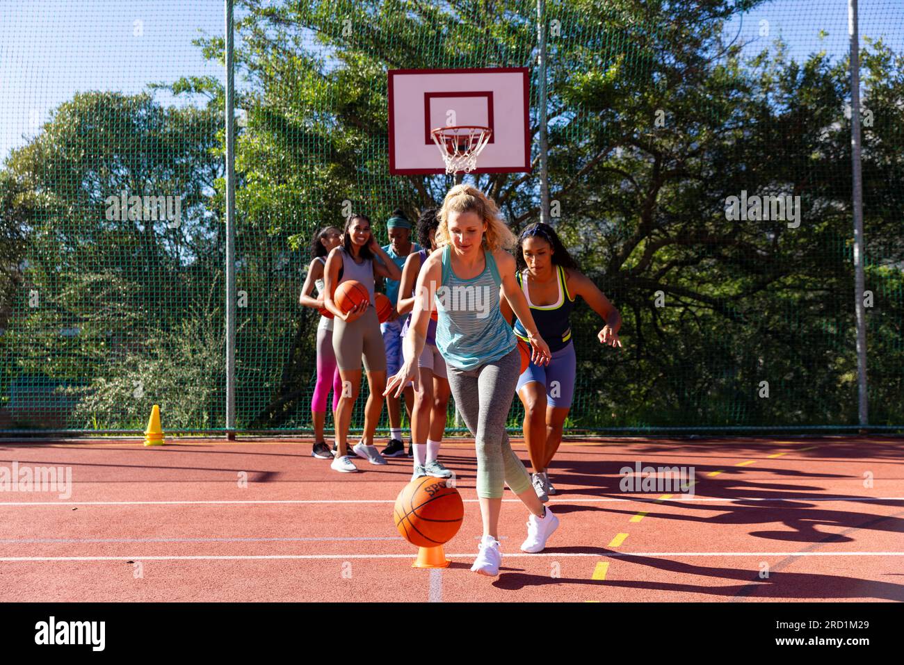 Diverse group of women exercising with basketball at basketball court ...
