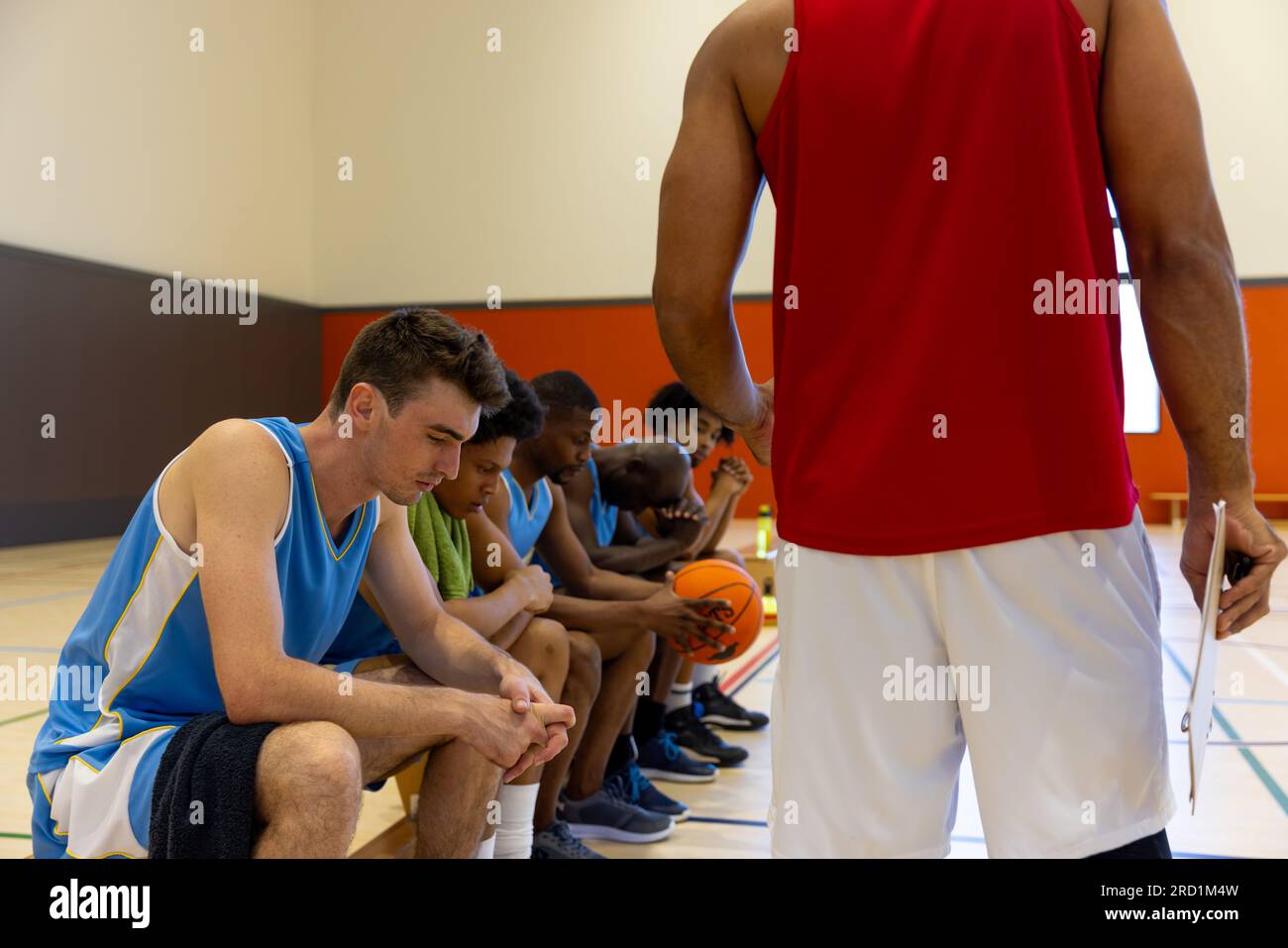Diverse male basketball players discussing game plan with coach ...