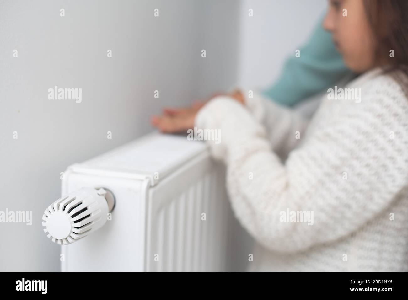 Child warming hands on heating radiator near white wall, closeup Stock ...