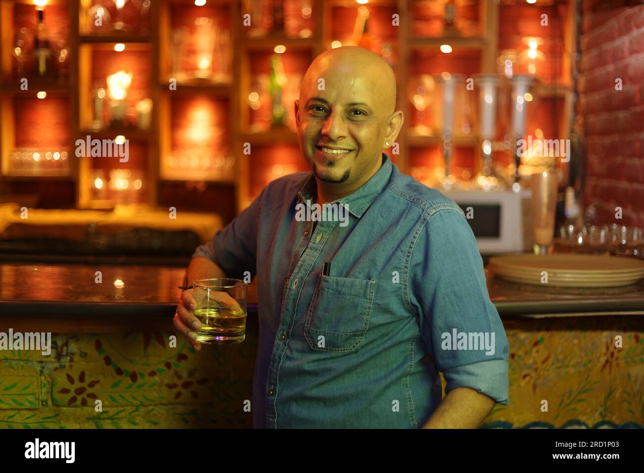 Dramatic shot of young and flamboyant handsome bald guy standing on bar ...
