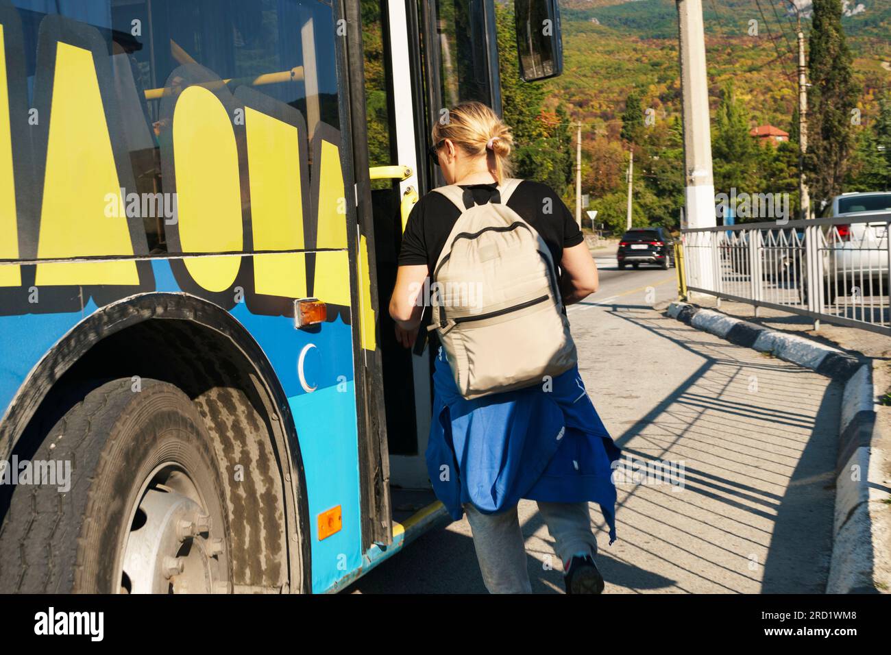 A young girl tourist enters the bus on a mountain transport route Stock ...