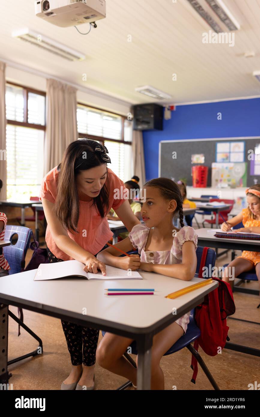 Happy diverse female teacher with band teaching schoolgirls reading in ...