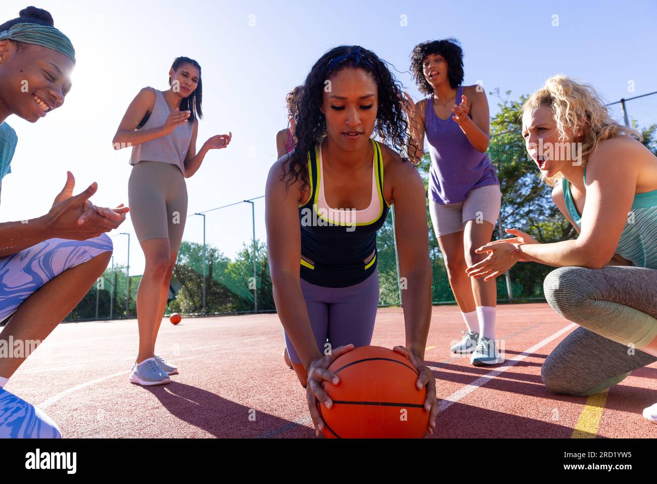 Happy diverse group of women doing push ups with basketball and ...