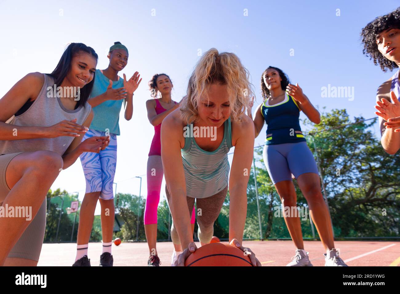 Happy diverse group of women doing push ups with basketball and ...