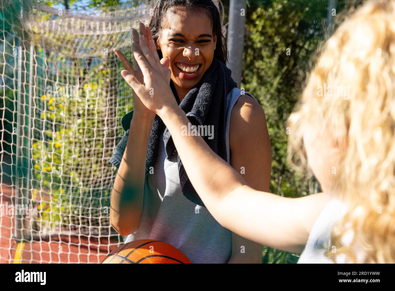Happy diverse female friends high fiving and holding basketball at ...