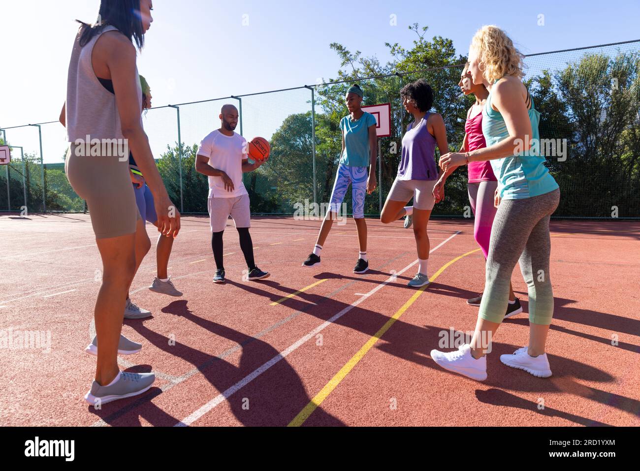 Diverse group of women with male coach stretching and warming up at ...