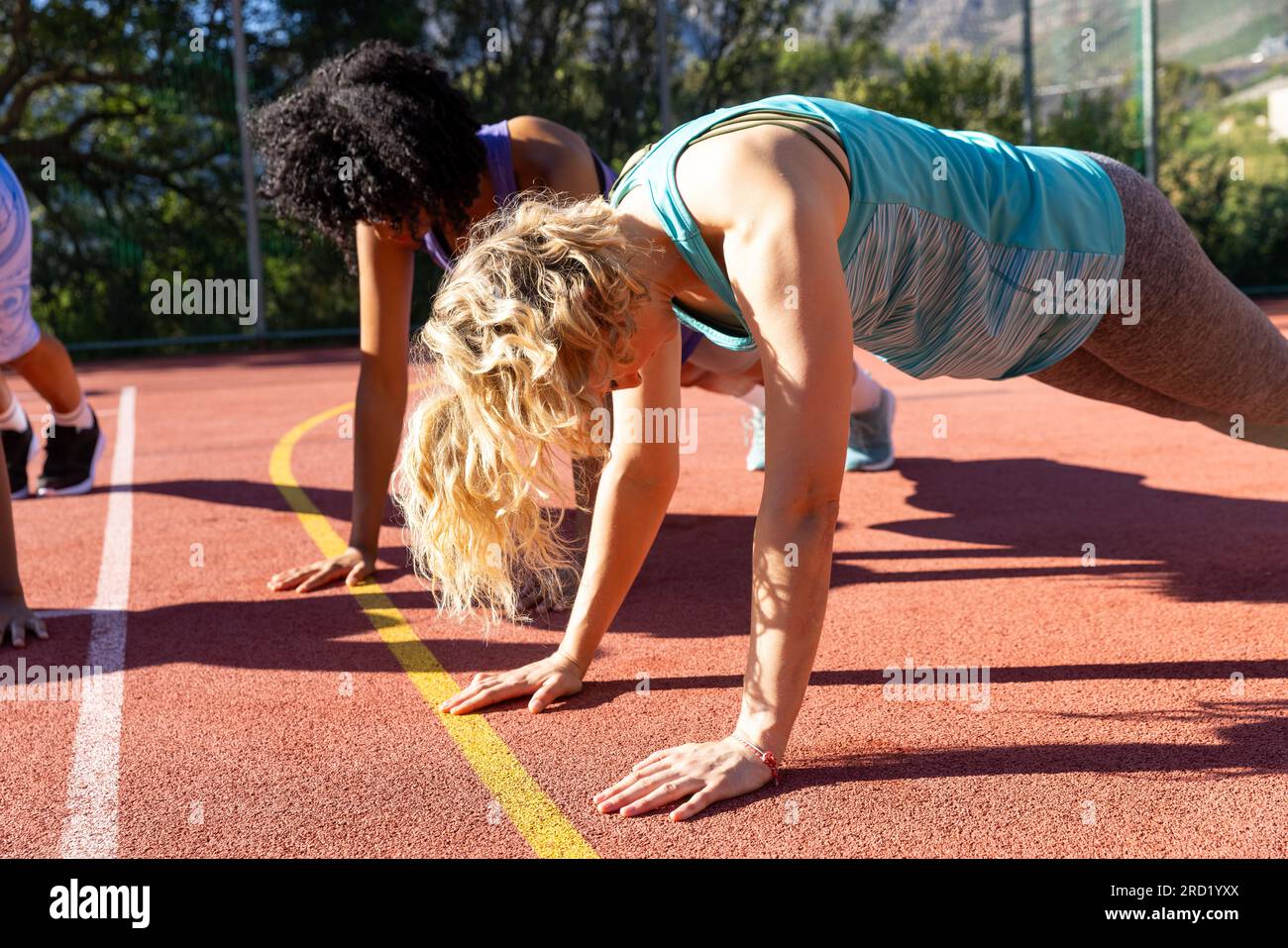 Diverse group of women doing push ups and warming up at basketball ...