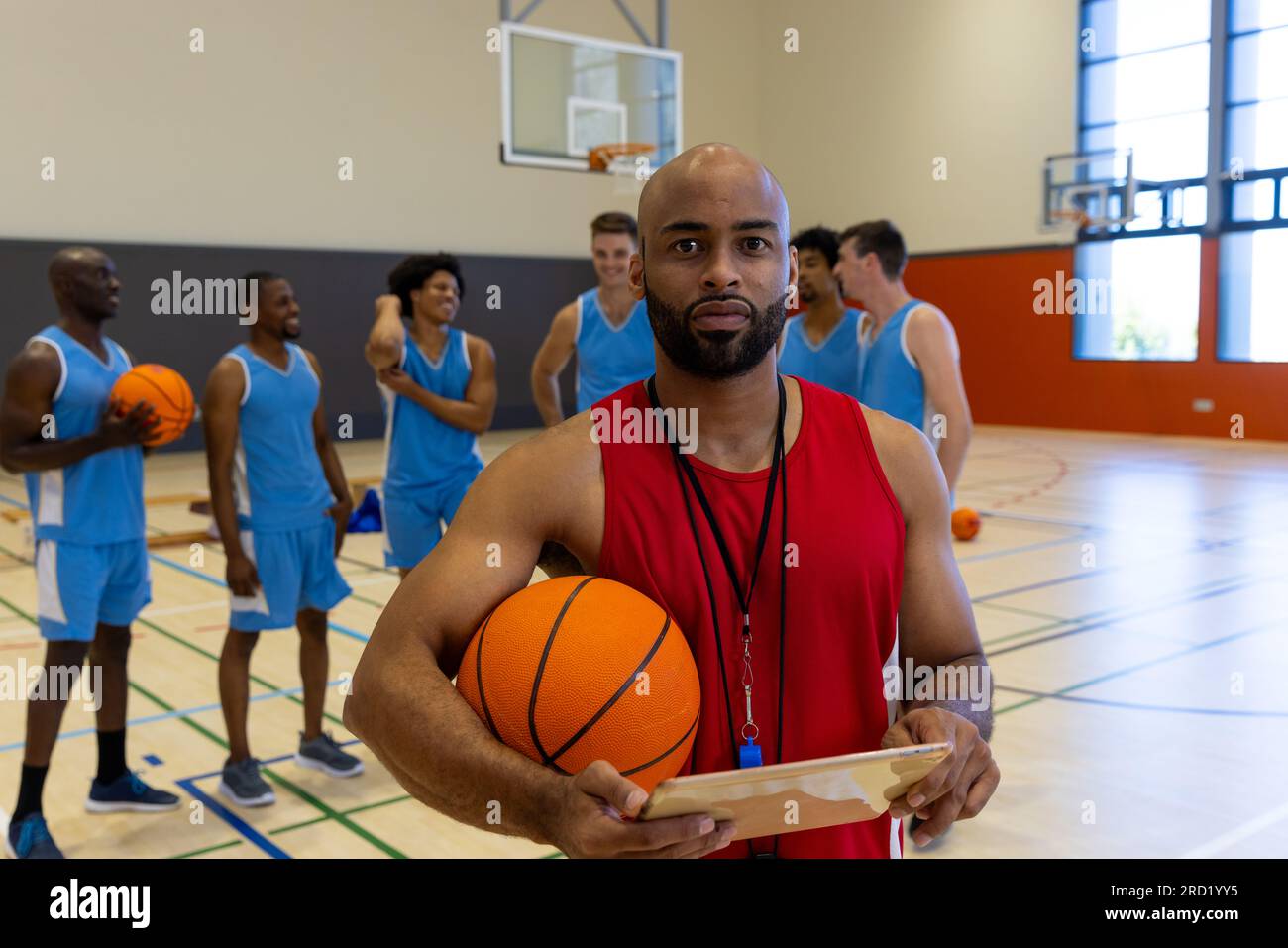 Portrait of biracial male coach with tablet over happy male basketball ...