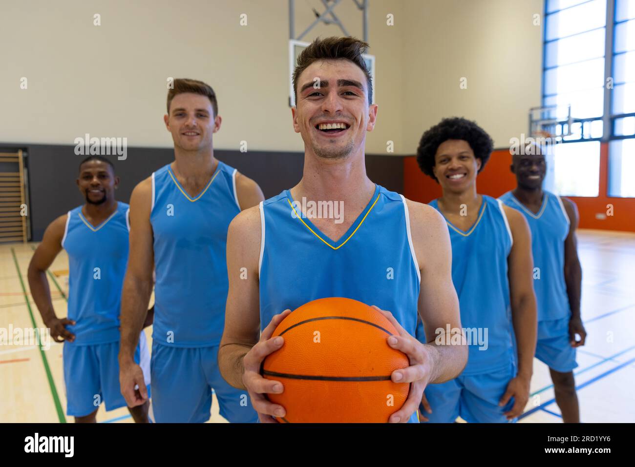 Portrait of happy diverse male basketball players wearing blue sports ...