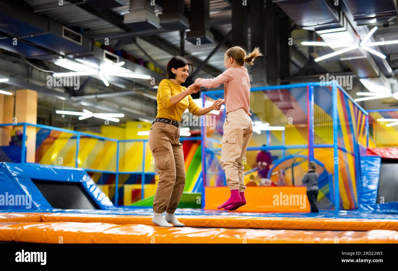 Pretty girl and her daughter kid jumping on colorful trampoline at ...