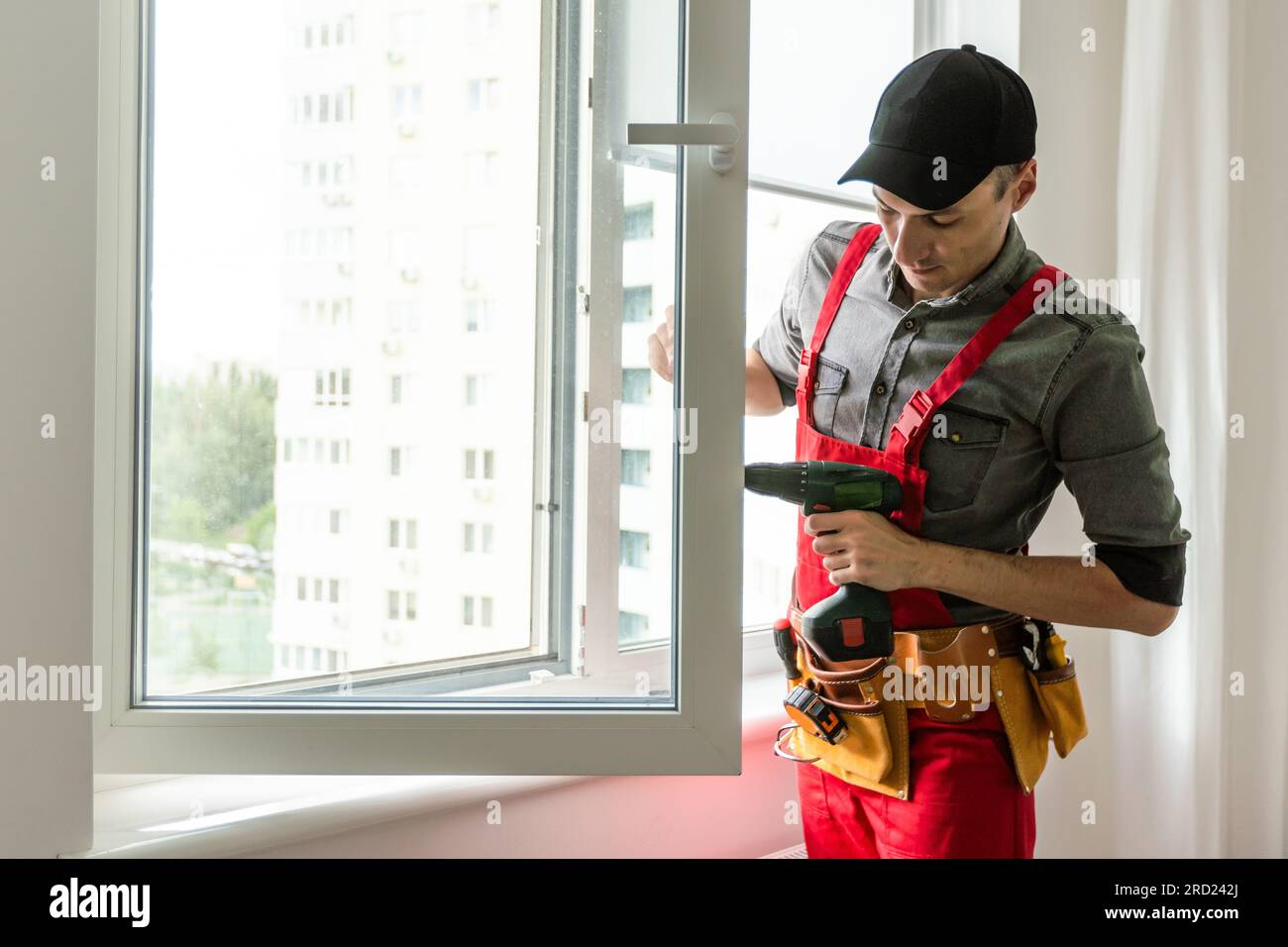 Workman in overalls installing or adjusting plastic windows in the ...